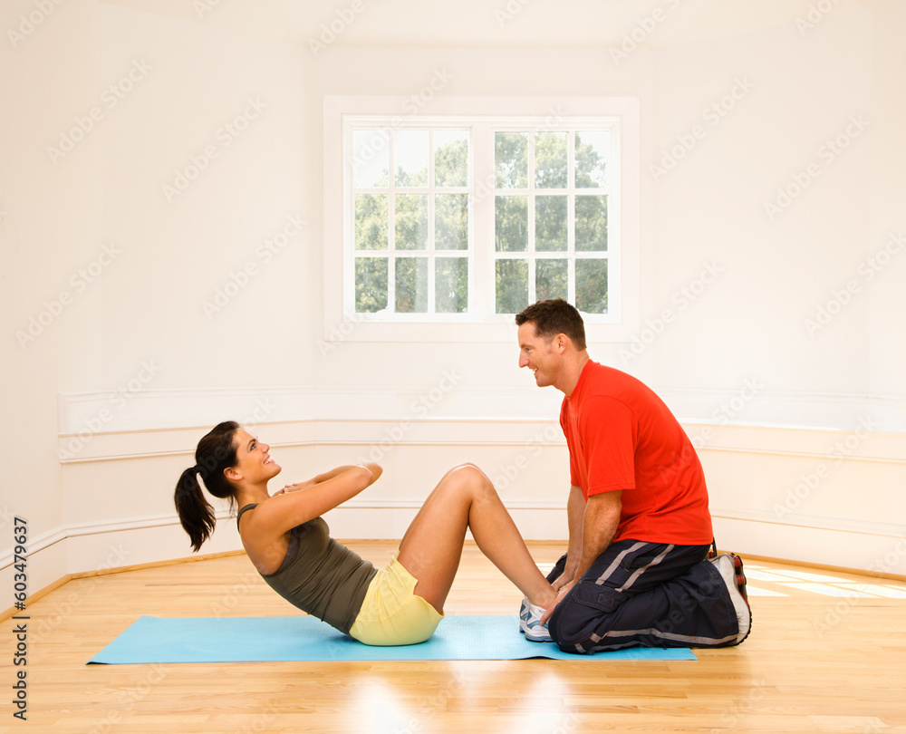 Foto de Man holding woman's feet down as she does sit up exercises. do ...