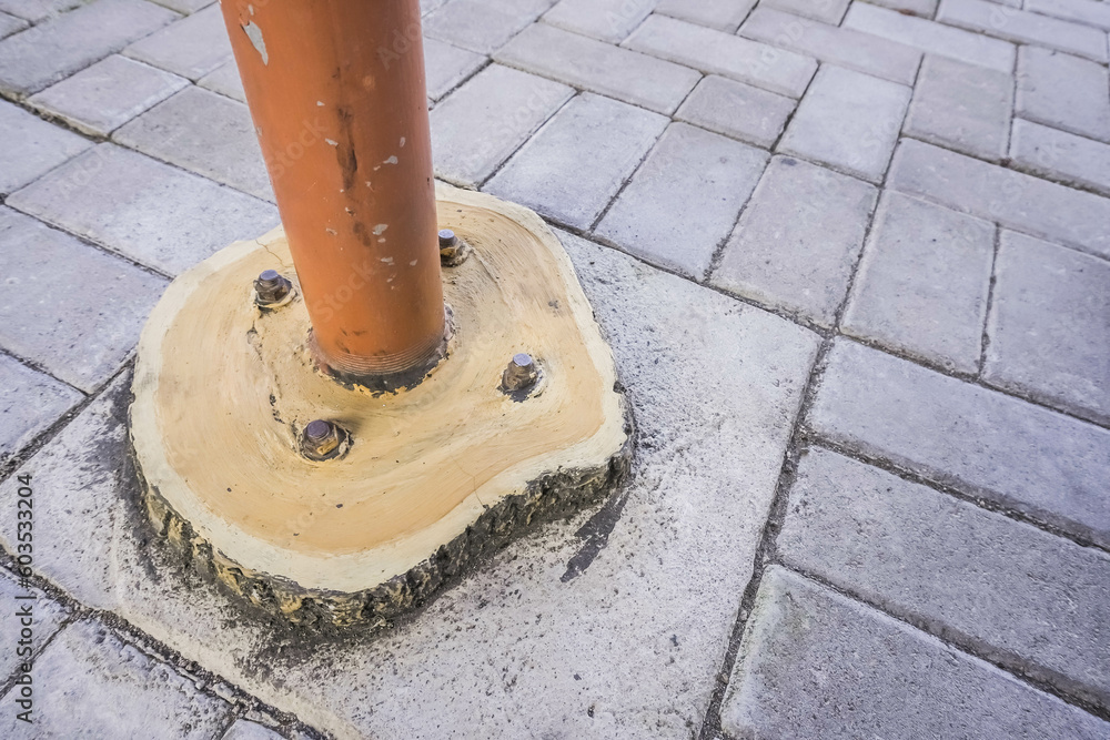 Metal pillar fastened to block paving with anchor bolts and nuts ...