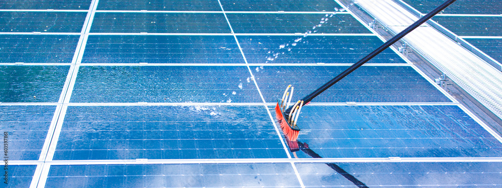 Professional worker cleaning solar panels with brush and washing with ...