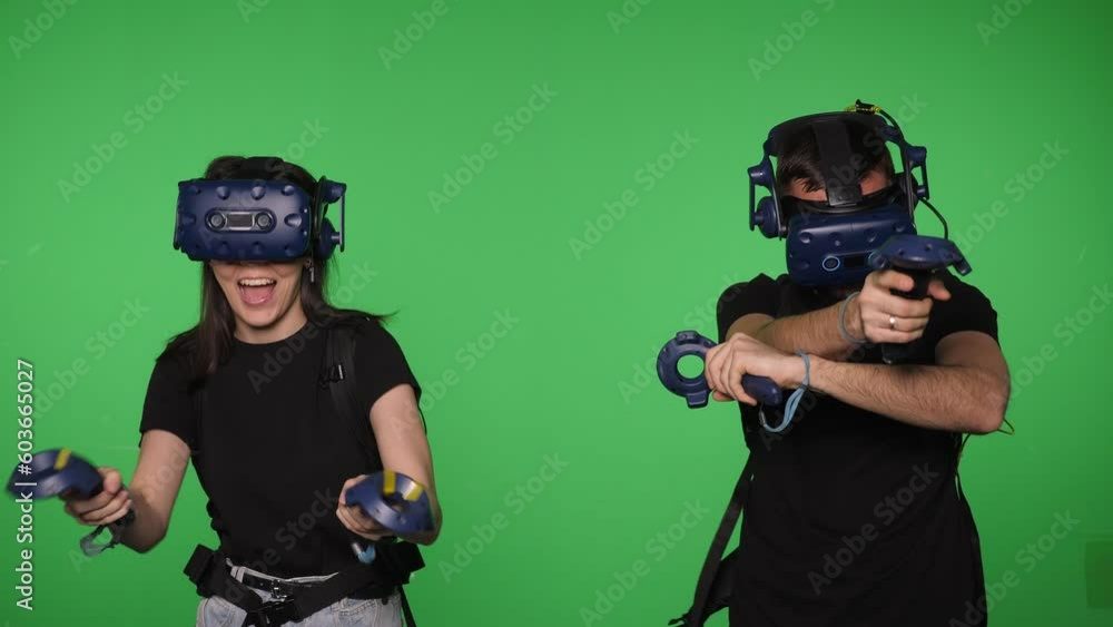 An active couple in VR glasses with joysticks is playing a video game ...