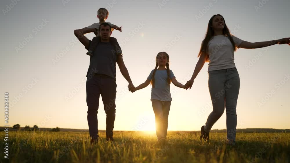 Happy family at sunset.People holding hands walk along green grass ...