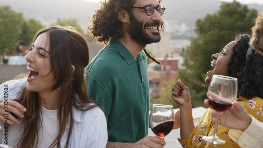 Multiracial group of friends dancing and drinking red wine at rooftop ...