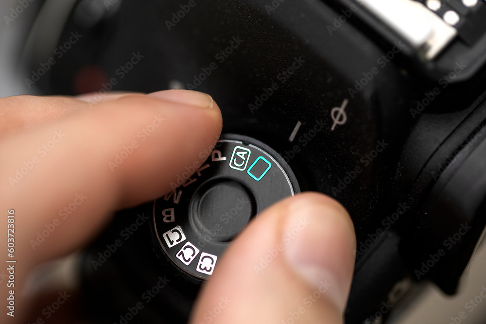 Fingers selecting automatic mode on a professional camera. man putting the automatic mode on the ...
