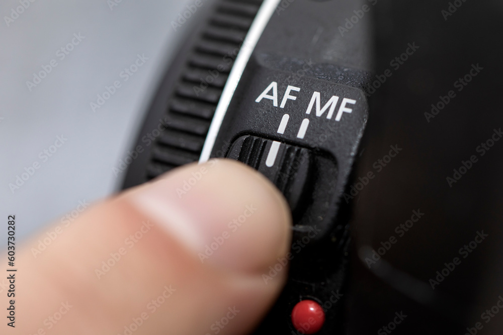 Fingers selecting autofocus AF on a professional camera lens. man ...