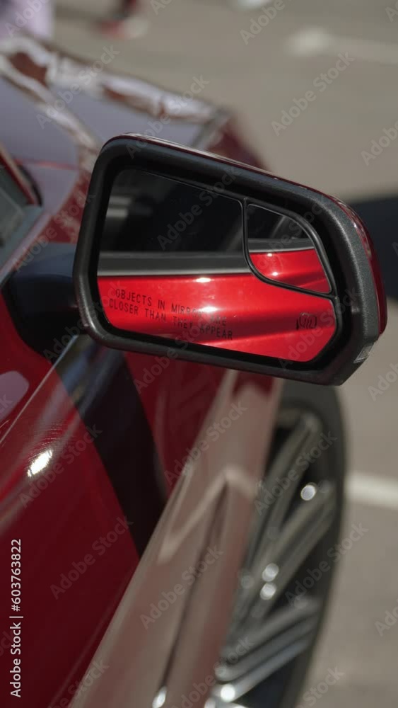 Mirror of American red muscle car in sunny parking lot with warning ...
