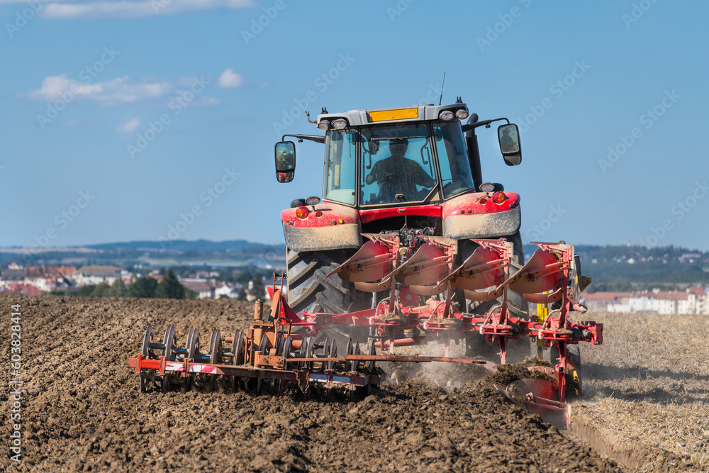 Red tractor on field at plowing and harrowing farm land soil in summer ...
