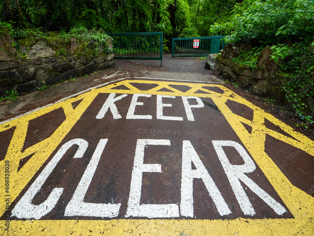 Big and bald keep clear sign on a road by entrance to a park. Warning ...