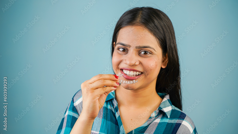 Young Asian Indian woman holding removable invisible aligner, also ...