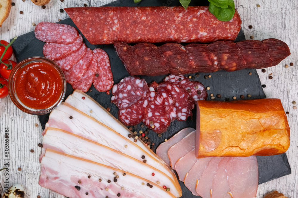 Antipasti different types of sausages and lard on a graphite board .Top ...