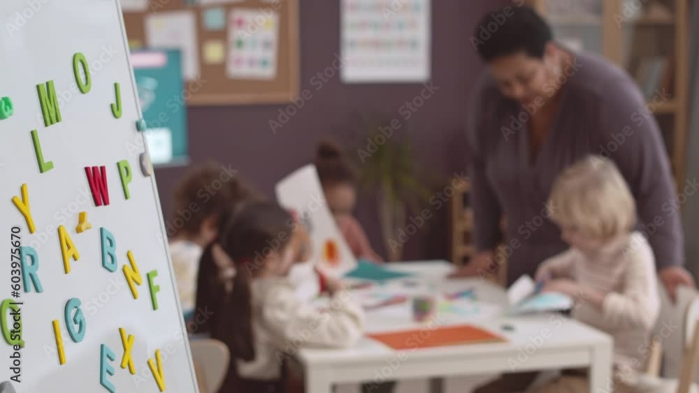 Whiteboard with colorful letters of alphabet in focused foreground with ...