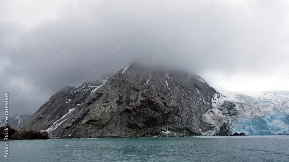 Glacier meeting the Southern Ocean at the base of a rock cliff, off ...