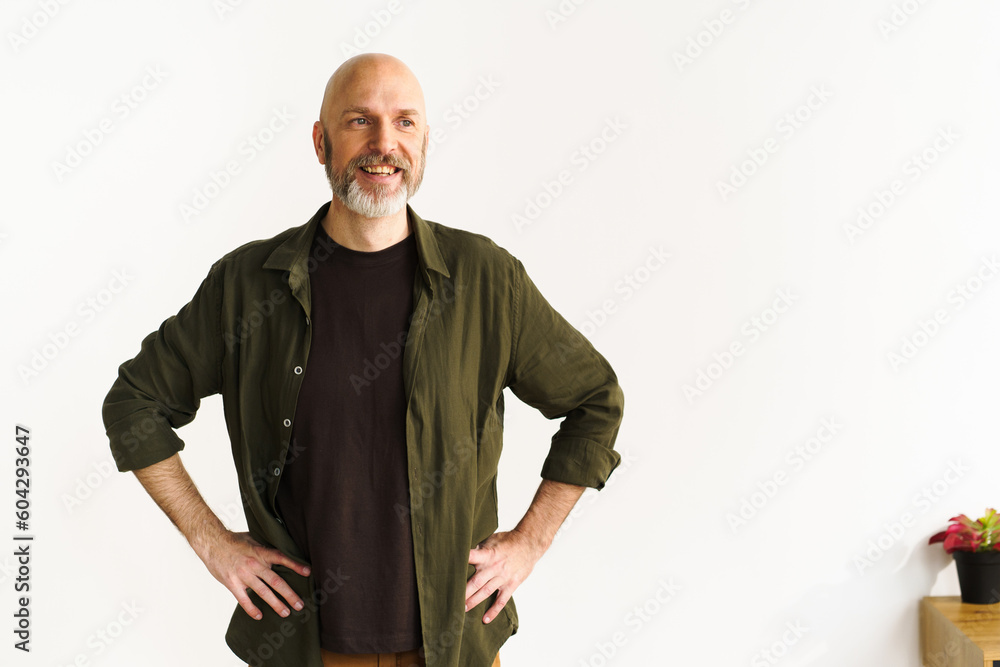 Smiling mid-aged bald man with silver beard standing confidently in ...