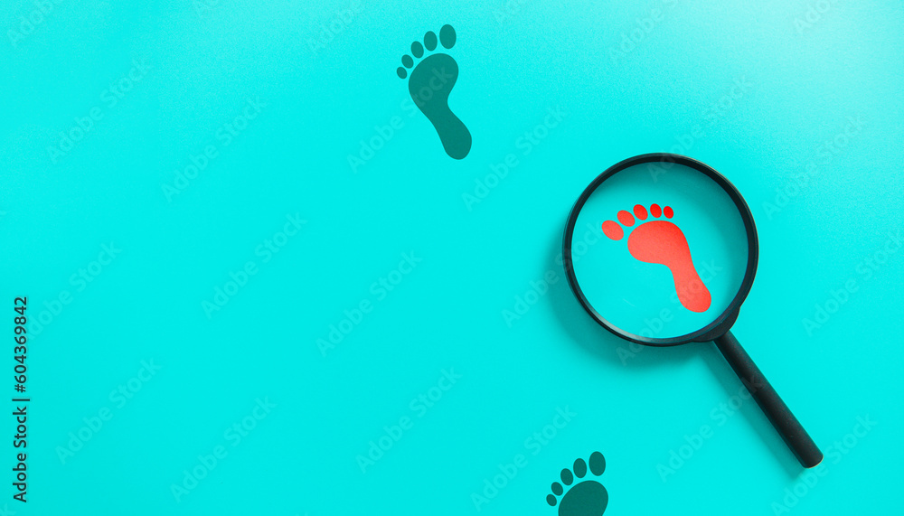 Magnifying glass magnifying red bare footprints on blue background ...