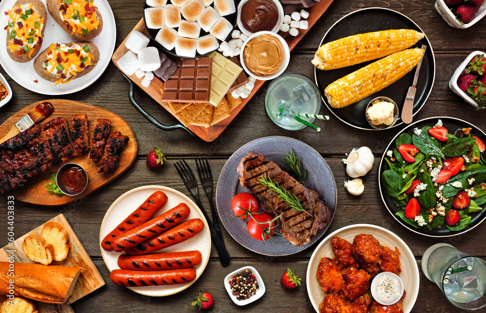 Summer BBQ food table scene over a white wood banner background ...