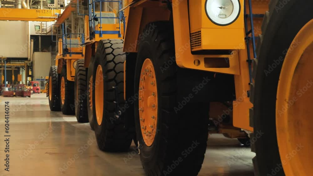 An assembly line of large dump trucks. Assembled trucks are lined up in ...