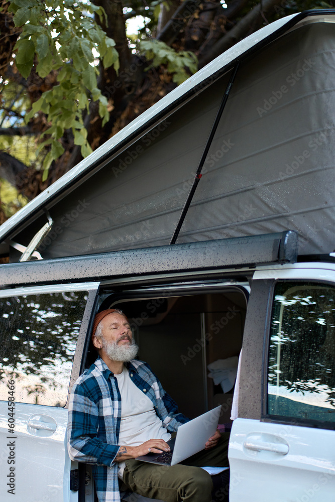Calm older man sitting in rv camper van using laptop. Peaceful mature ...