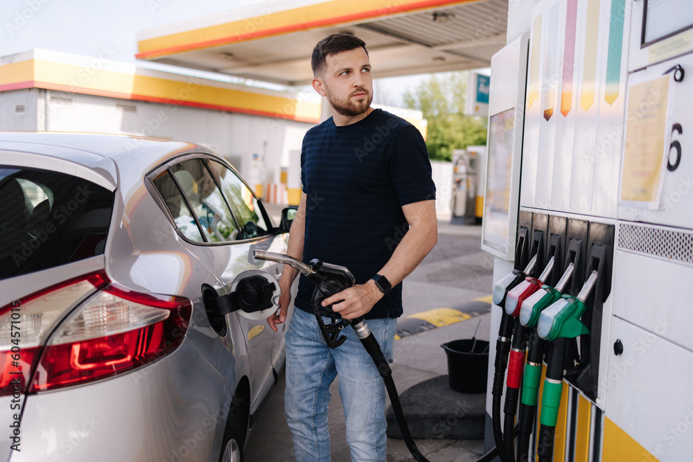 Handsome bearded man refueling car and looking on the scoreboard while ...