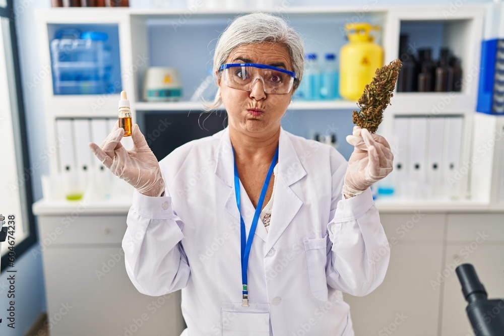 Middle age woman with grey hair doing weed oil extraction at laboratory ...