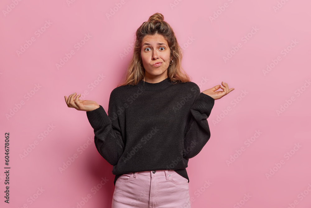 Shocked embarrassed woman purses lips spreads palms and shrugs ...