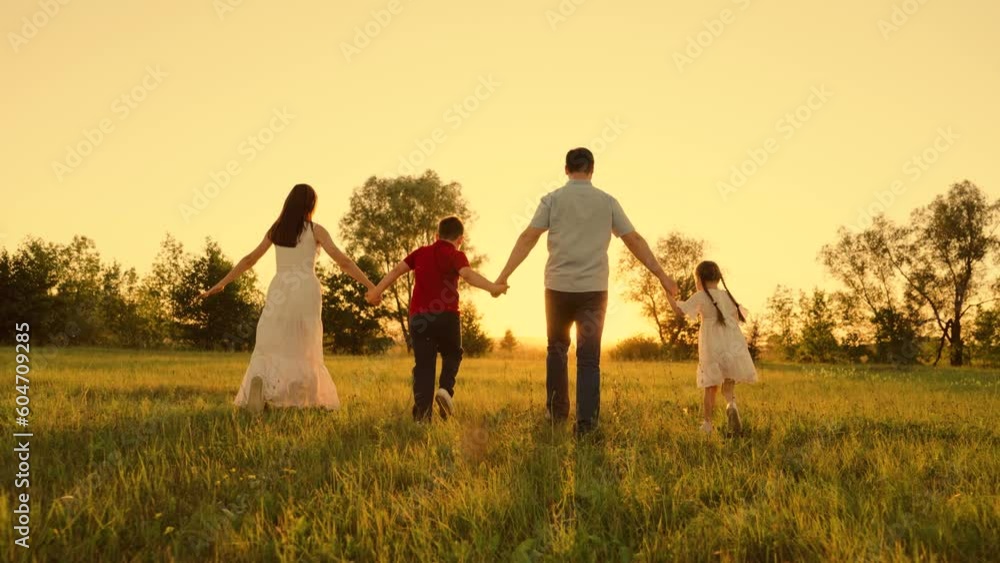 Happy family run forward on green grass park. Mom, dad, daughter, son ...