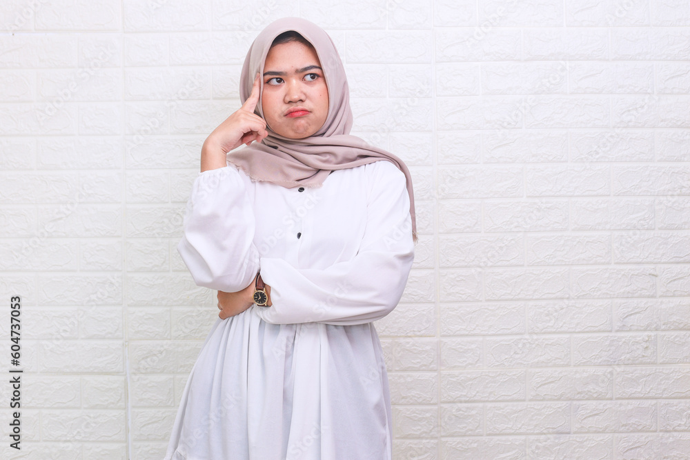 Young veiled muslim woman standing crossed arms putting a finger on the ...