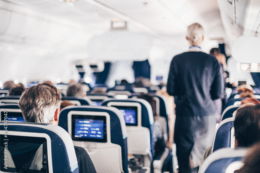 Interior of airplane with passengers on seats and stewardess in uniform ...