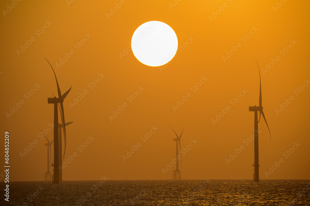 Fans of wind turbines spin over the sparkling sea. Dynamic clouds at ...
