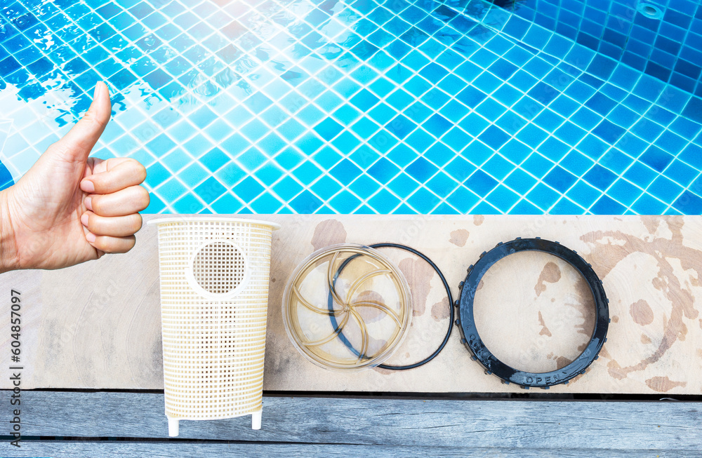 Swimming pool filter basket set on swimming pool edge with thumb up ...