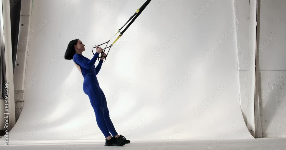 Woman in specialized sports clothing using a band with loops to perform ...