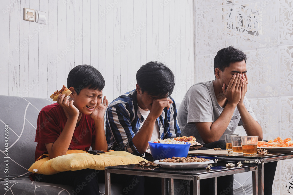 Asian sibling family sitting on couch in living room and watching scary ...