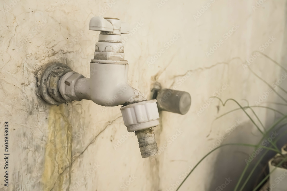 Old weathered white water faucet on the wall. Concept for save water ...
