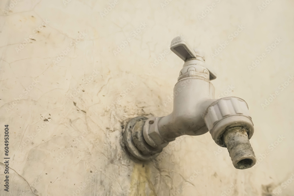 Old weathered white water faucet on the wall. Concept for save water ...
