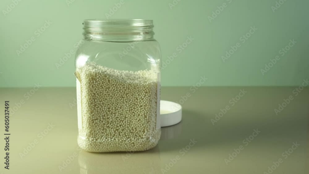 Tapioca pearls or white sago balls are poured with measuring spoon into ...