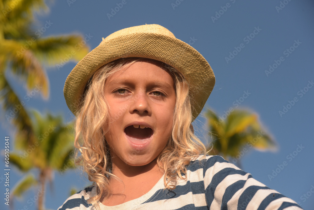 Beautiful boy 8 years old walks outside. The kid wears a hat, shorts ...