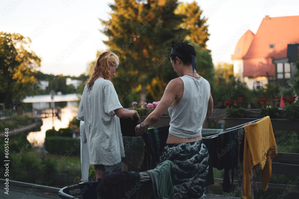 queer couple hang clothes washing together on balcony by lake Stock ...