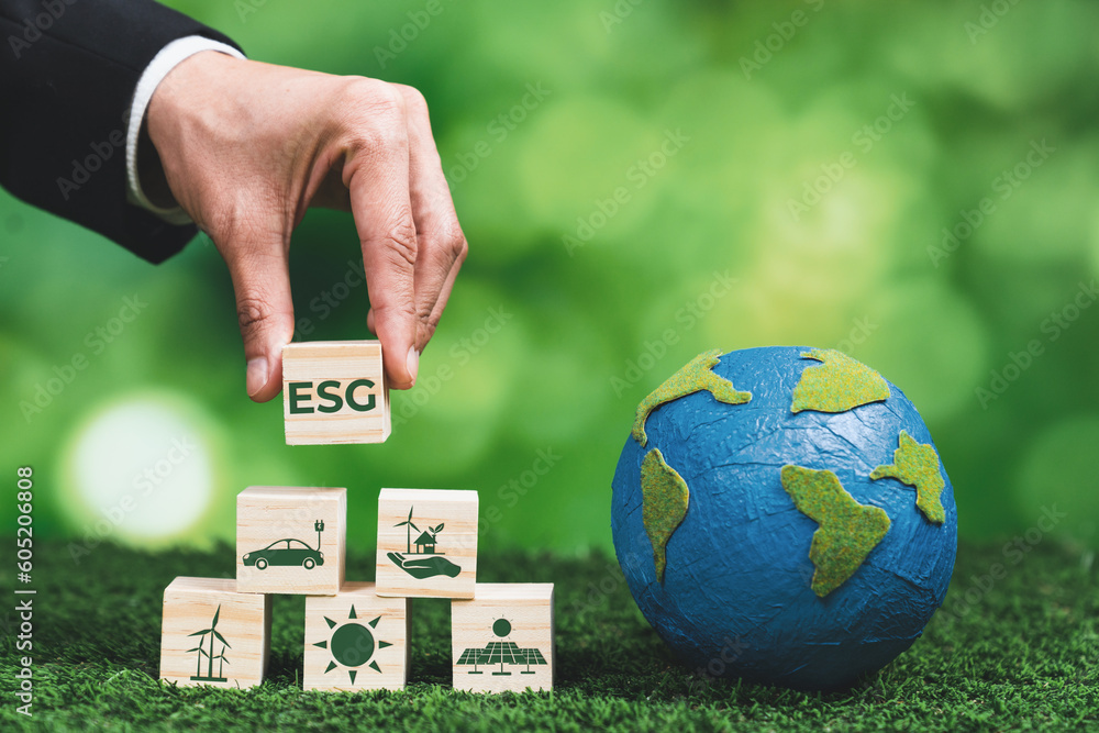 Businessman holding paper earth planet with ESG symbol wooden cube ...