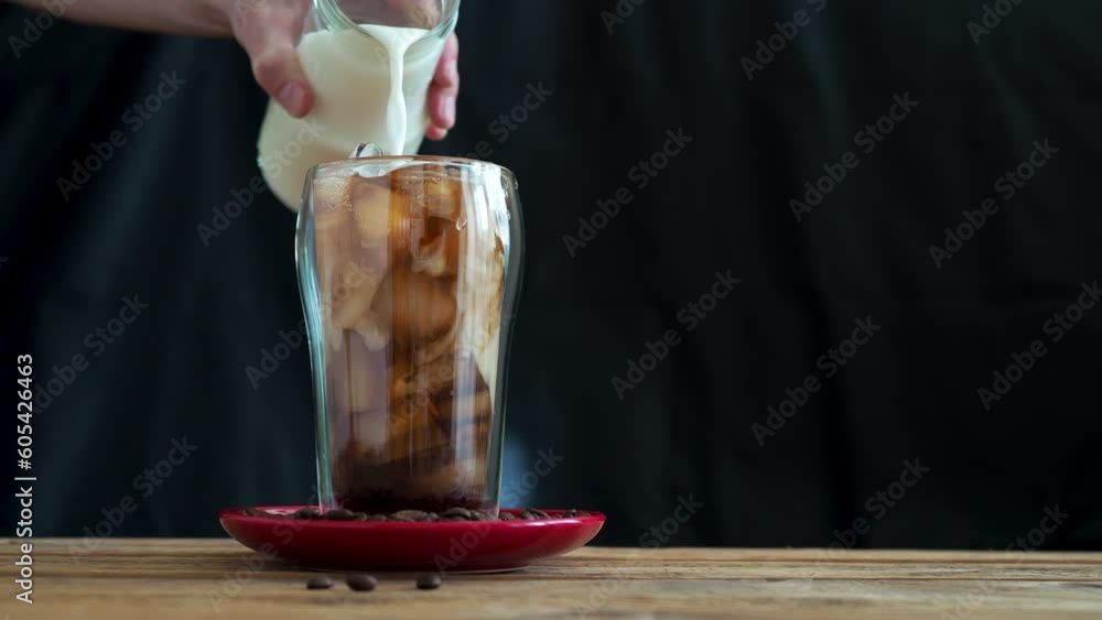 Ice coffee in a tall glass and pouring milk from above with coffee ...