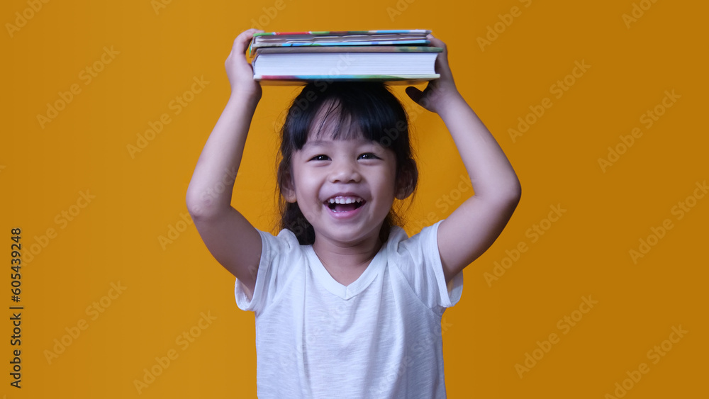 A little girl laughs with book on head. Smart child with a book. Little ...