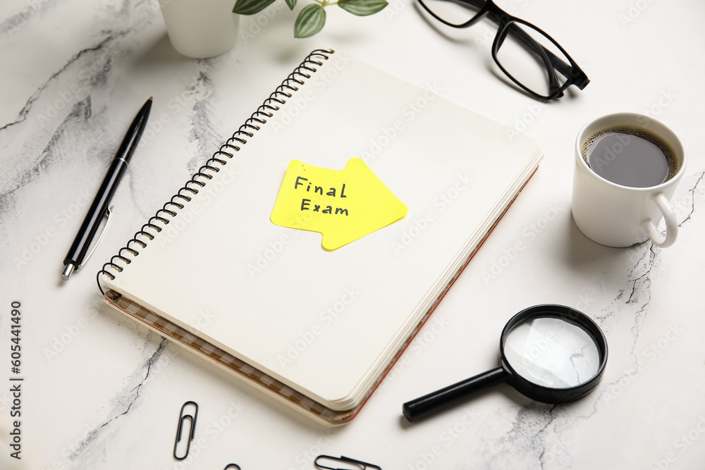 Sticky note with text FINAL EXAM, notebook, magnifier and cup of coffee ...