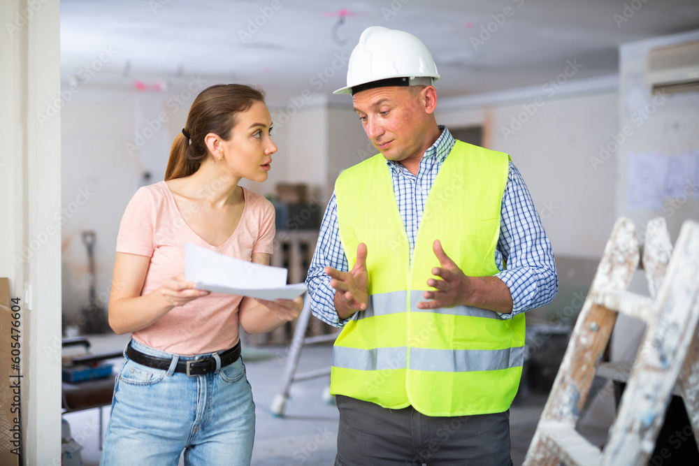 Woman apartment owner and man builder discussing repair works plan and ...