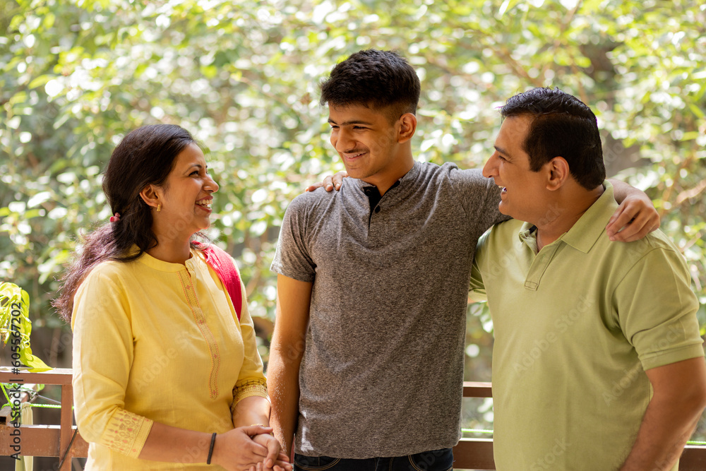 Happy parents with their teenage son standing together on balcony Stock ...