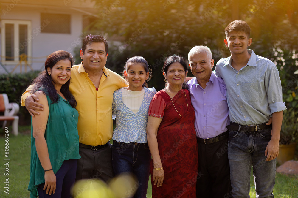 Multi generation happy Indian family standing together in backyard ...