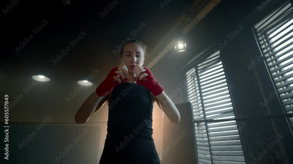 Serious woman fighter boxer wraps hands wrists with boxing bandage sits ...
