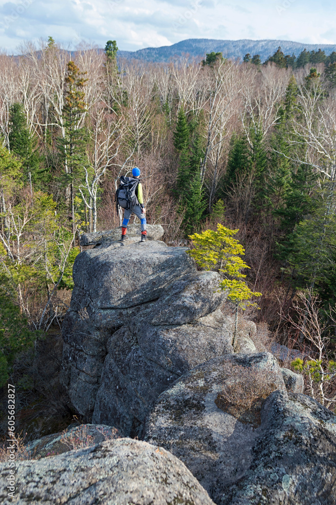 Tourist with backpack standing on the top of the rock in the spring ...