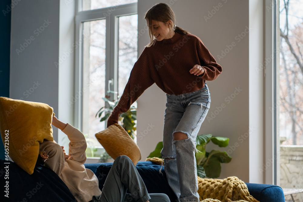 Happy kids brother and sister having pillow fight on couch at home ...