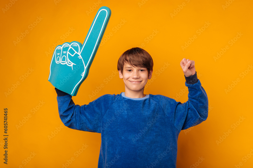 Happy teen boy wearing blue foam finger fan glove makes the winner ...