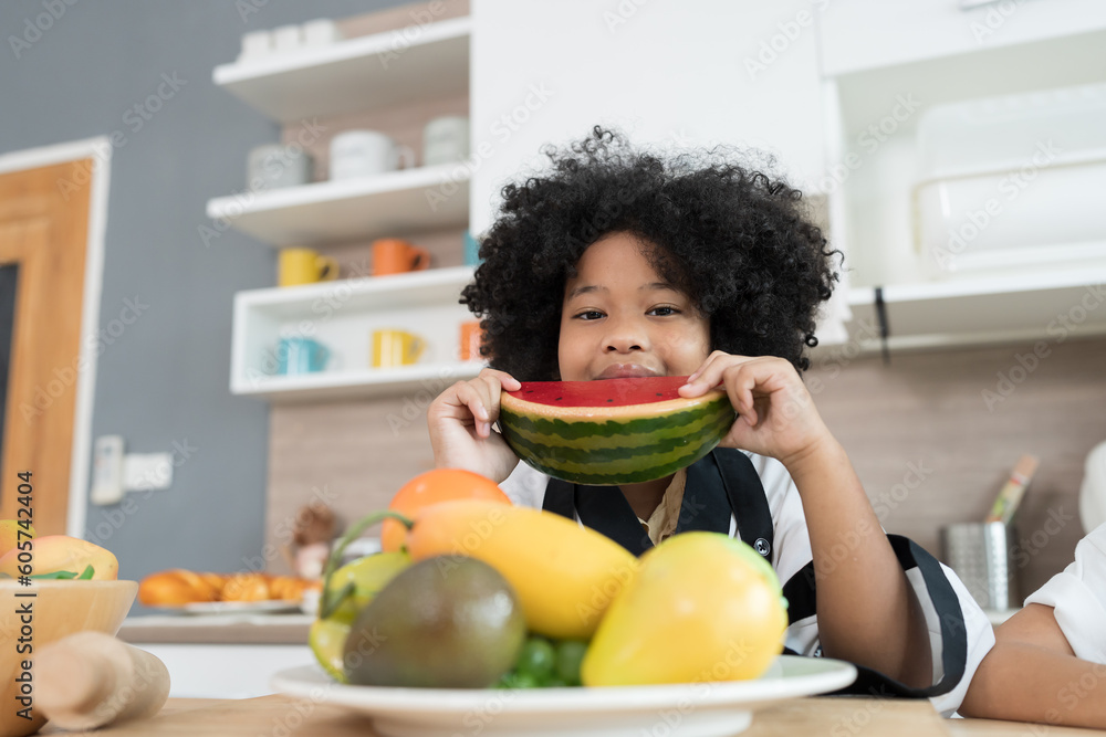 Foto de Happy child girl eating watermelon in the kitchen. Smiling ...