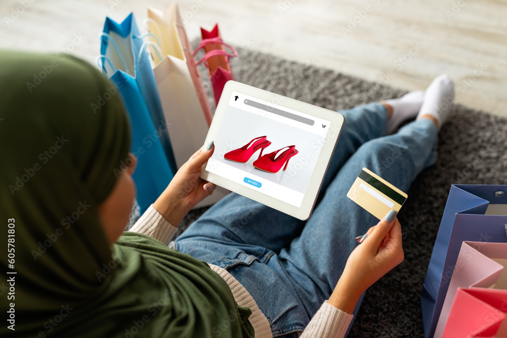 Young arabic woman in hijab using credit card and tablet with fashion ...