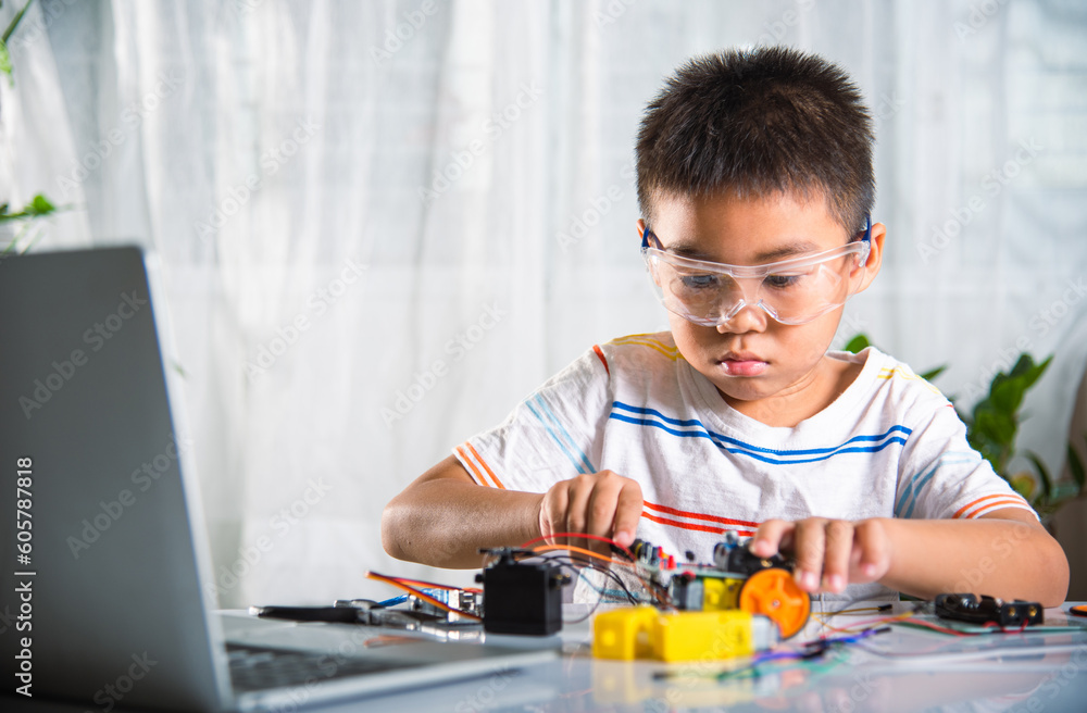 Asian kid boy assembling the Arduino robot car homework project at home ...