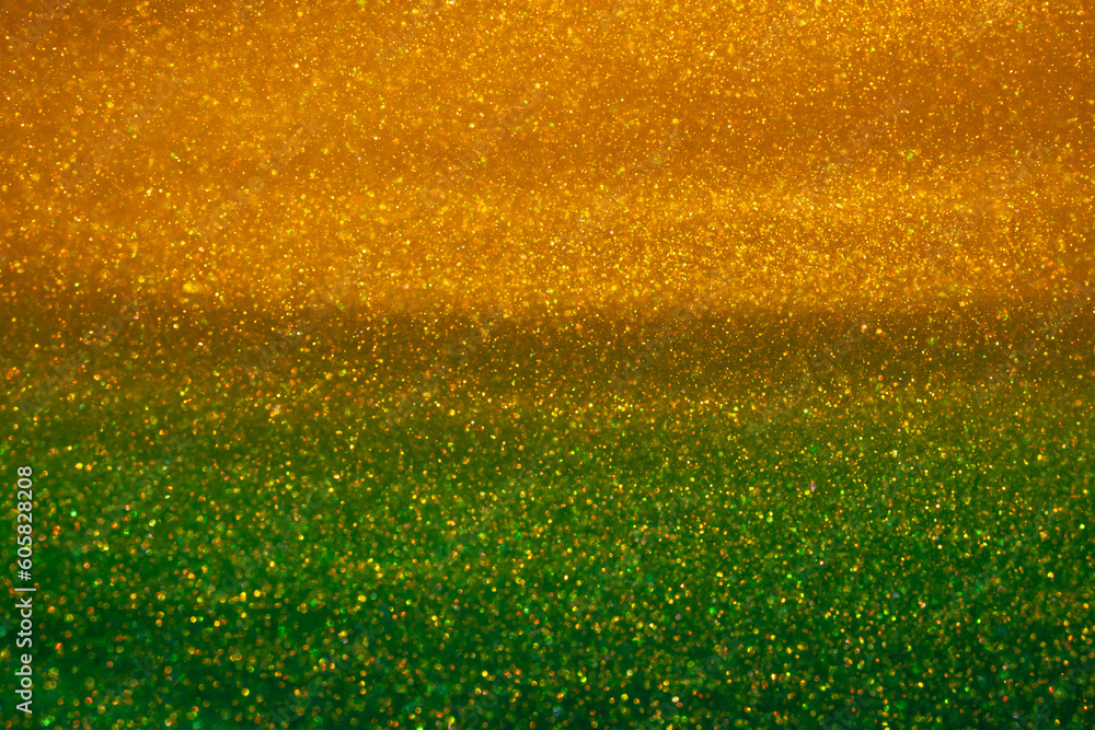 Glistening overflow of gold dust in a two-color liquid colored in green ...